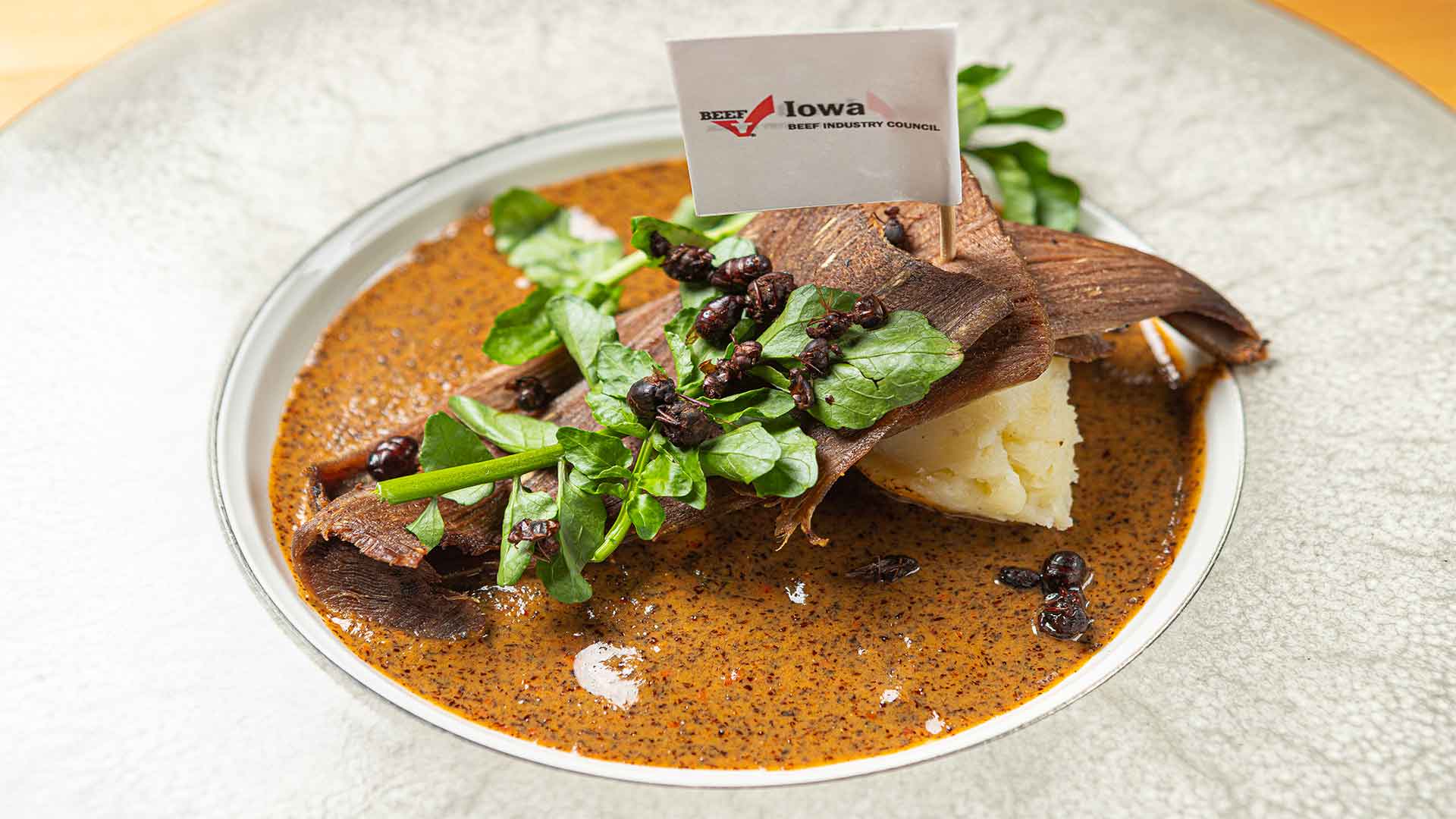 Lengua en mole de chicatana con puré de papa y berros